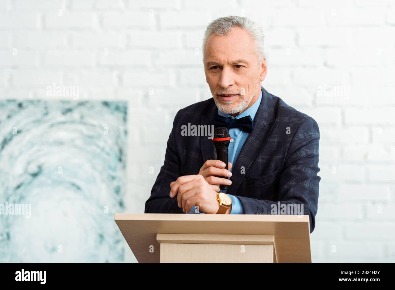 handsome auctioneer in suit talking with microphone during auction ...