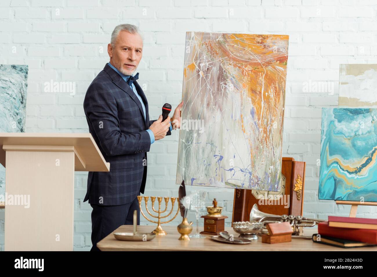 auctioneer talking with microphone and standing near picture during ...