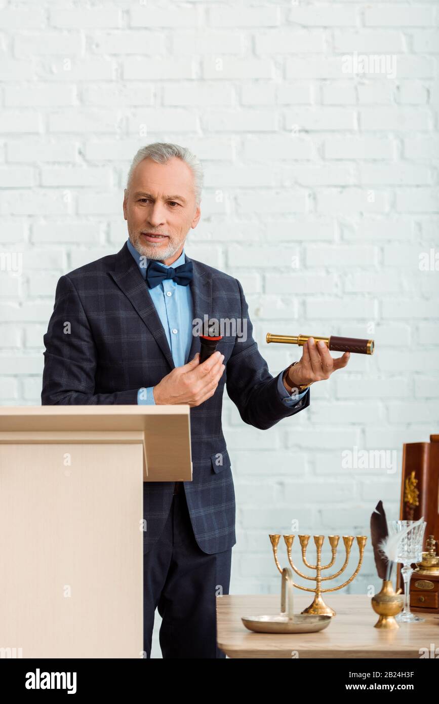 handsome auctioneer in suit talking with microphone and holding ...