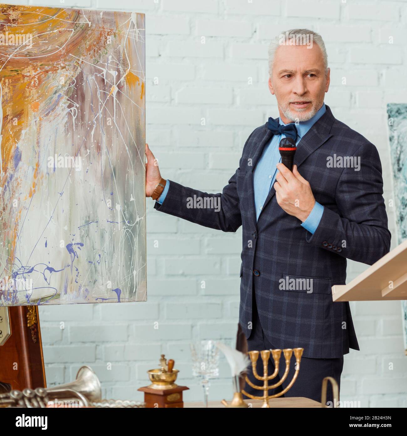 auctioneer talking with microphone and holding picture during auction ...