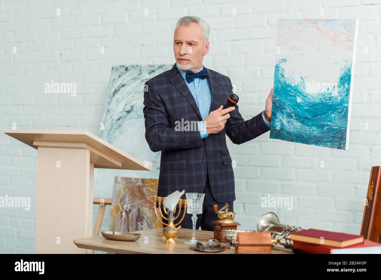 auctioneer in suit with microphone holding picture during auction Stock ...