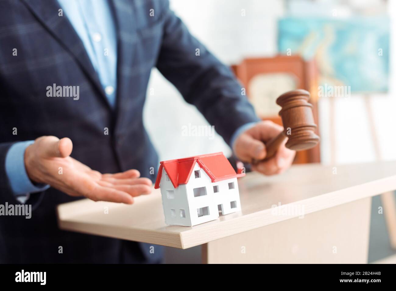 cropped view of auctioneer pointing with hand at model of house and ...