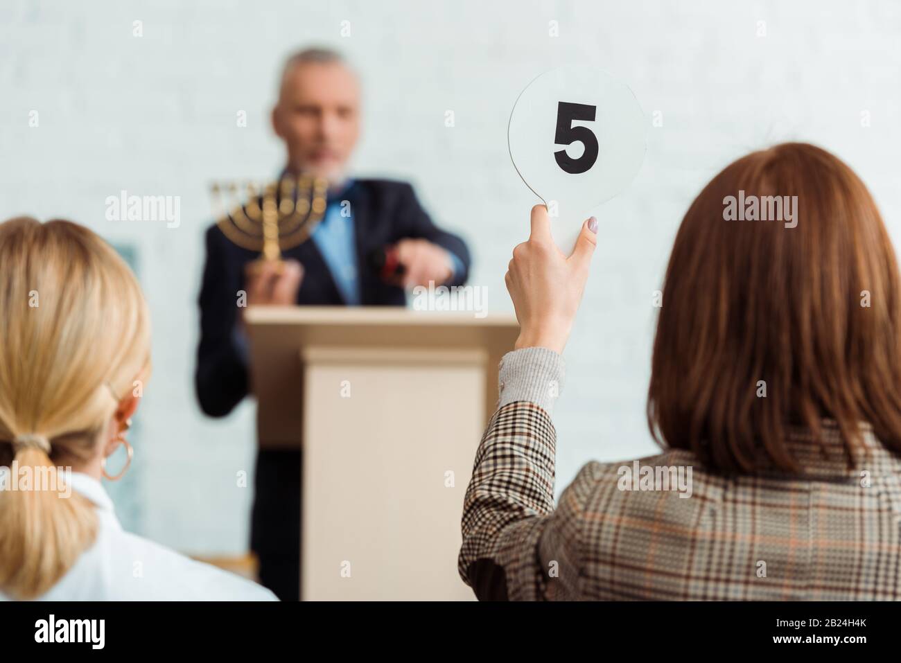 back view of buyer showing auction paddle with number five to ...