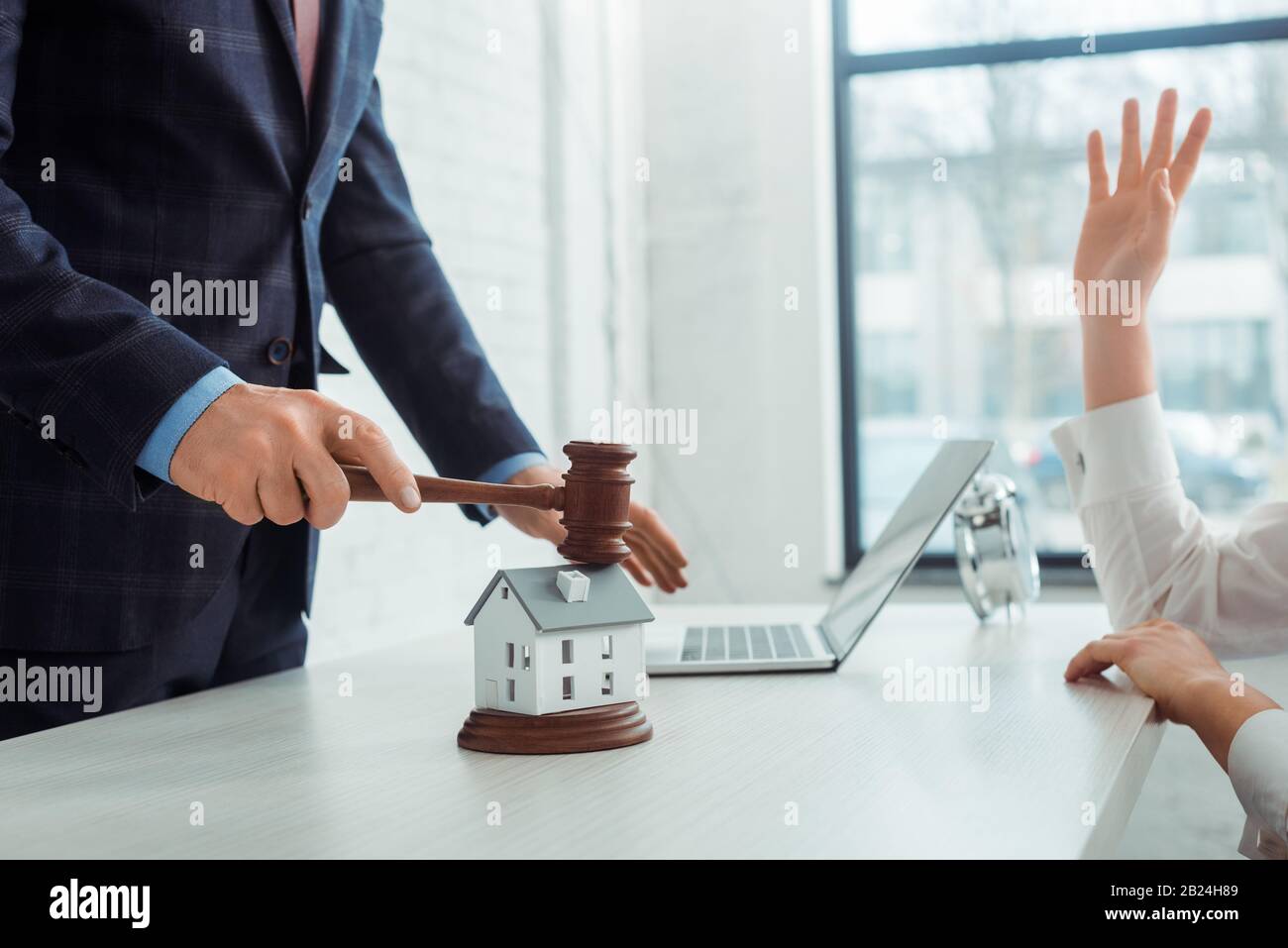cropped view of auctioneer hitting with gavel model oh house and woman ...
