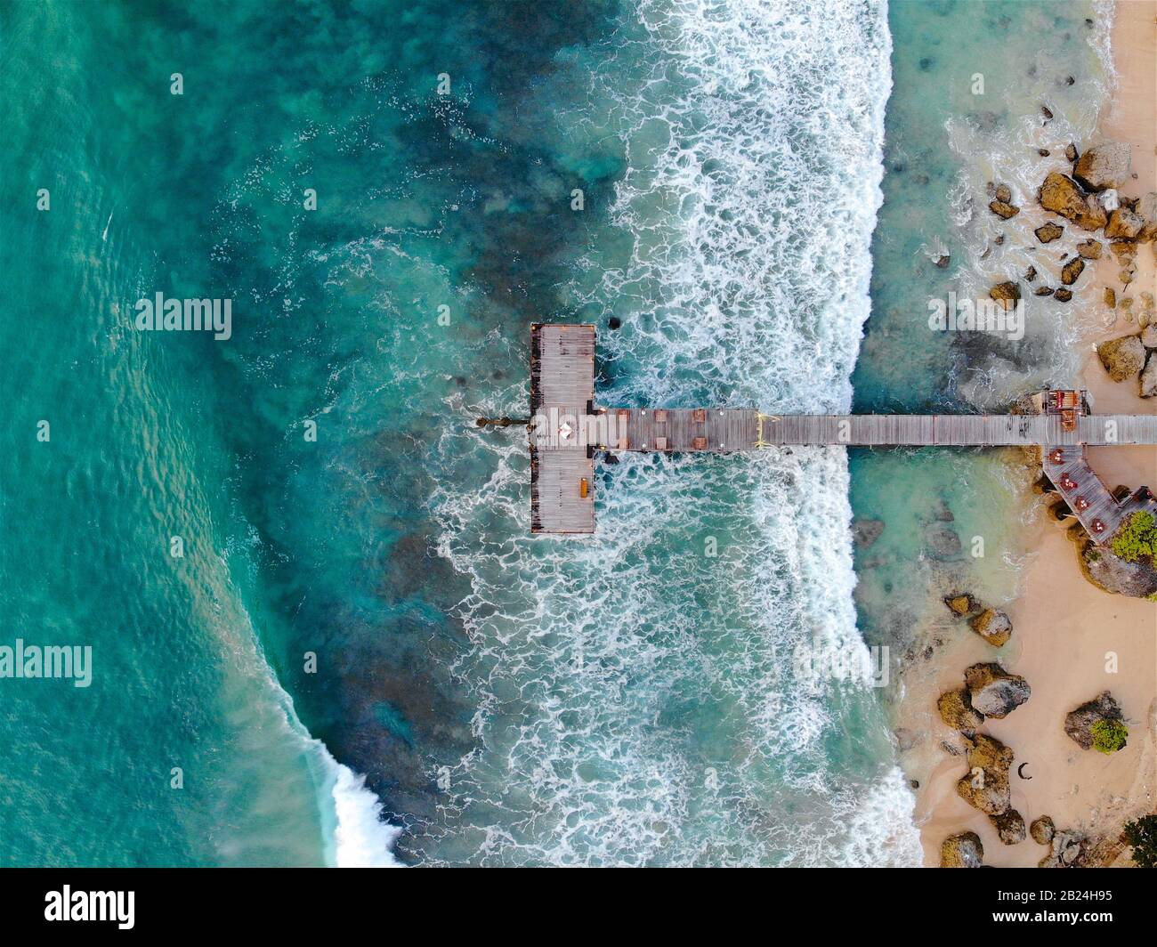 Aerial top view of dock over tropical blue water and sand beach, with ...