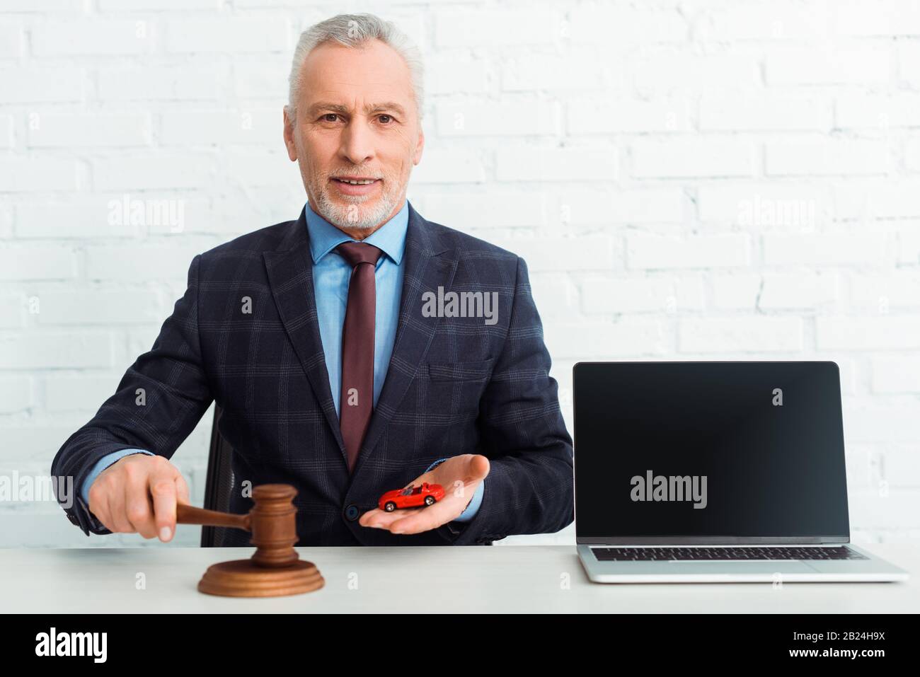 smiling auctioneer holding gavel and model of car near laptop Stock ...