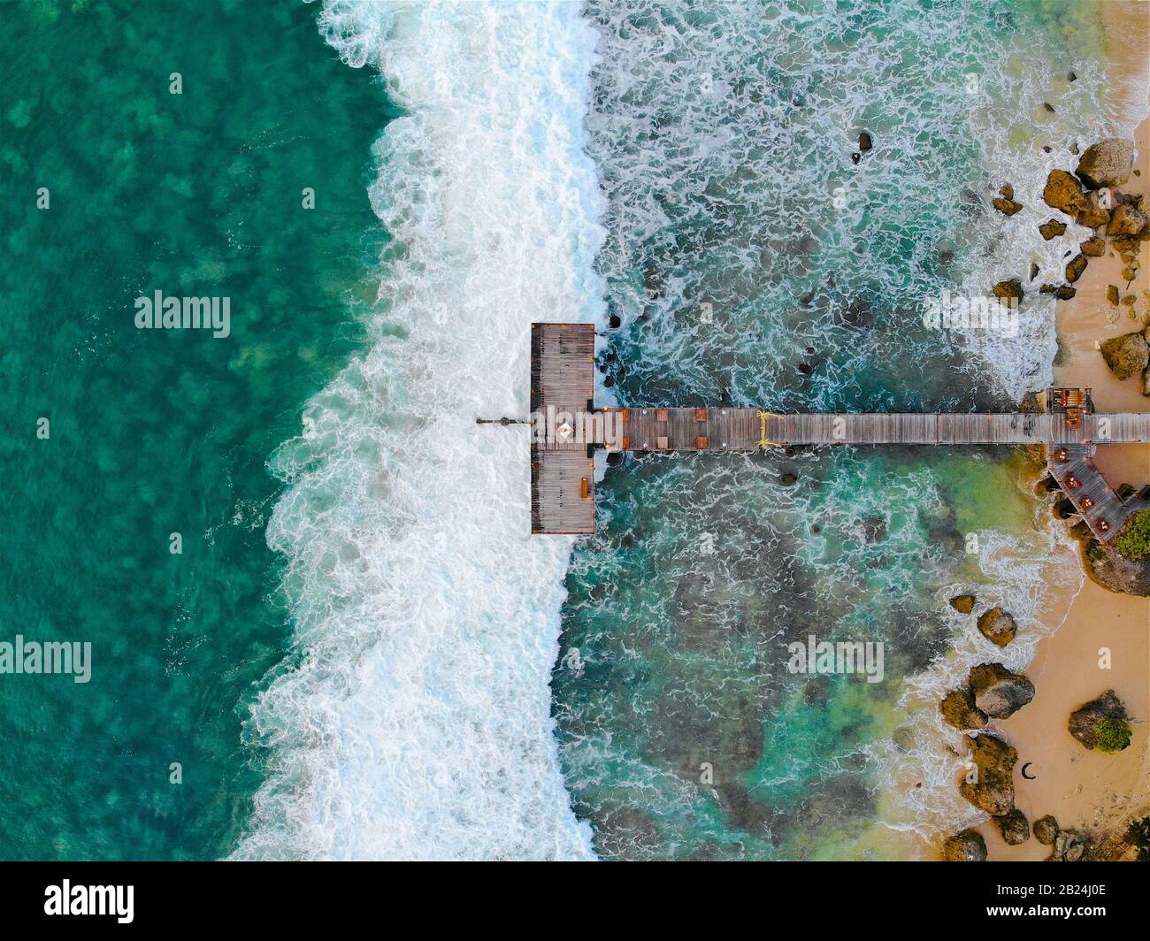 Aerial top view of dock over tropical blue water and sand beach, with ...