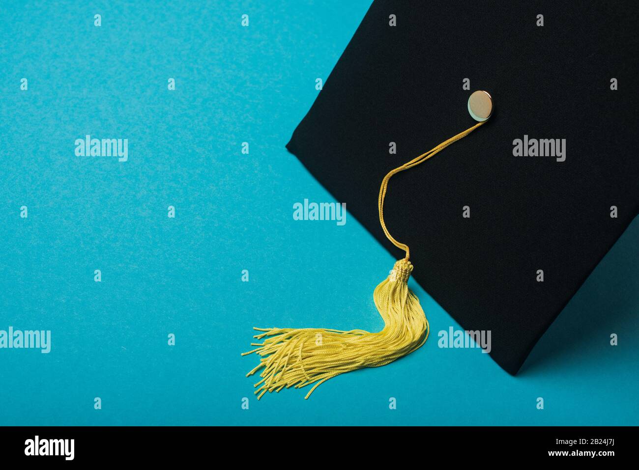 Graduation cap with yellow tassel on blue background Stock Photo - Alamy