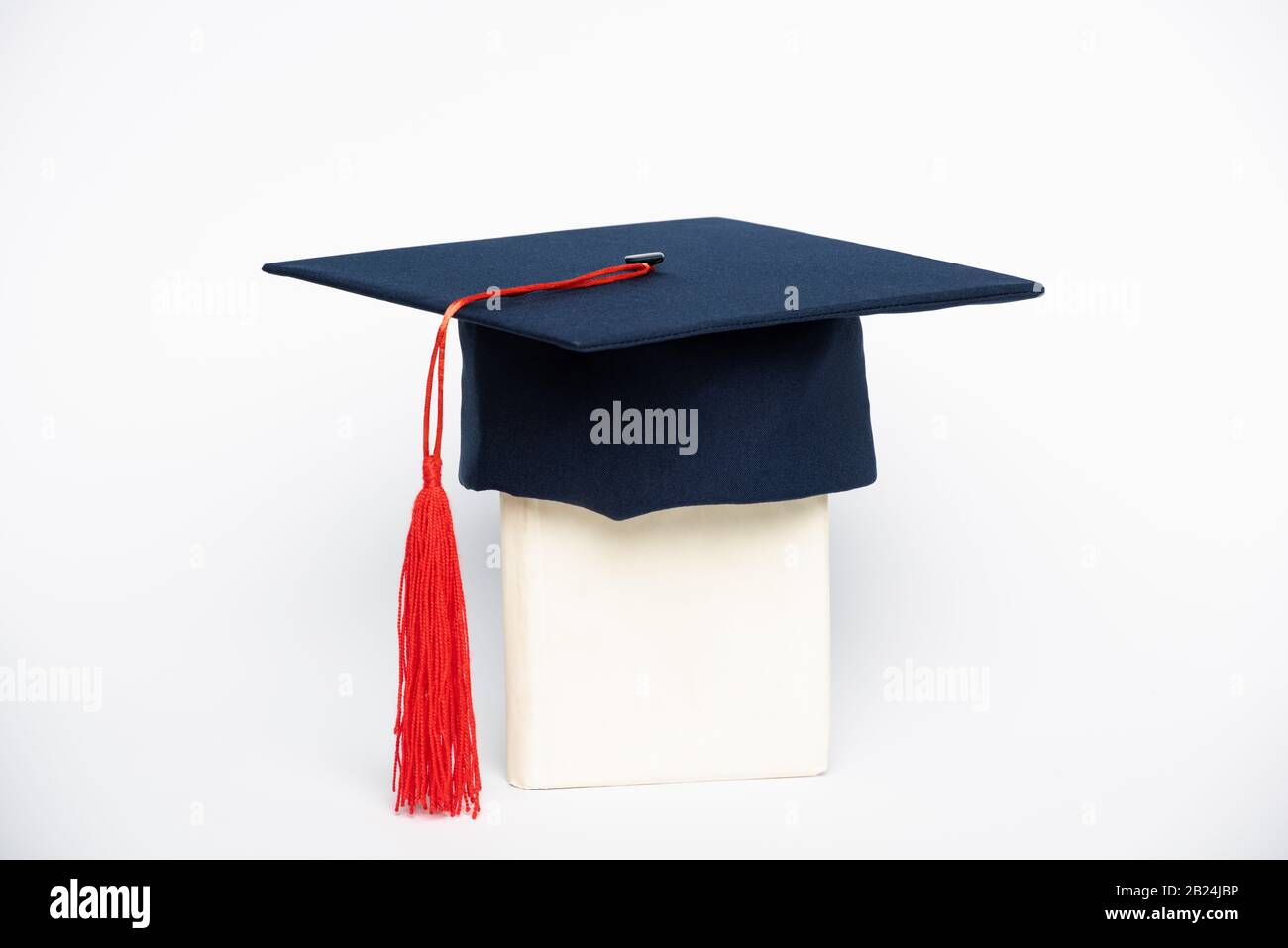Graduation cap with red tassel on book on white background Stock Photo ...