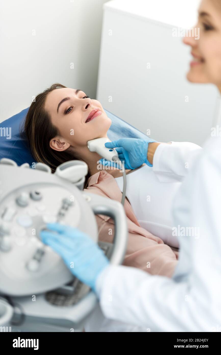 doctor examining thyroid of female patient with ultrasound scan in ...