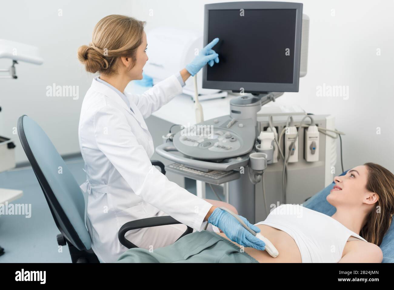 doctor making ultrasound scan of stomach to smiling patient and ...