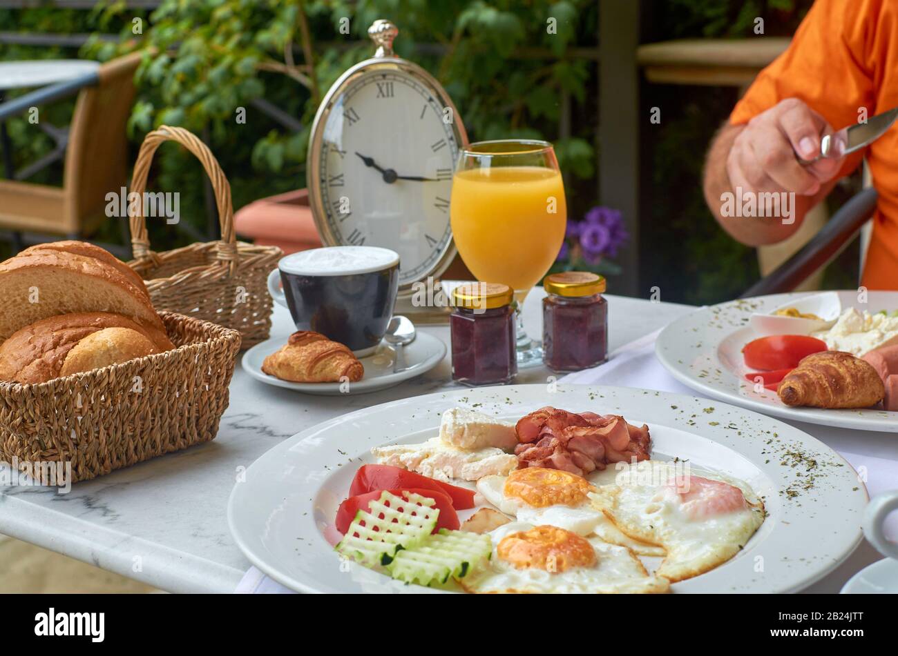 Delicious breakfast served with a cup of cappuccino. There is a clock ...