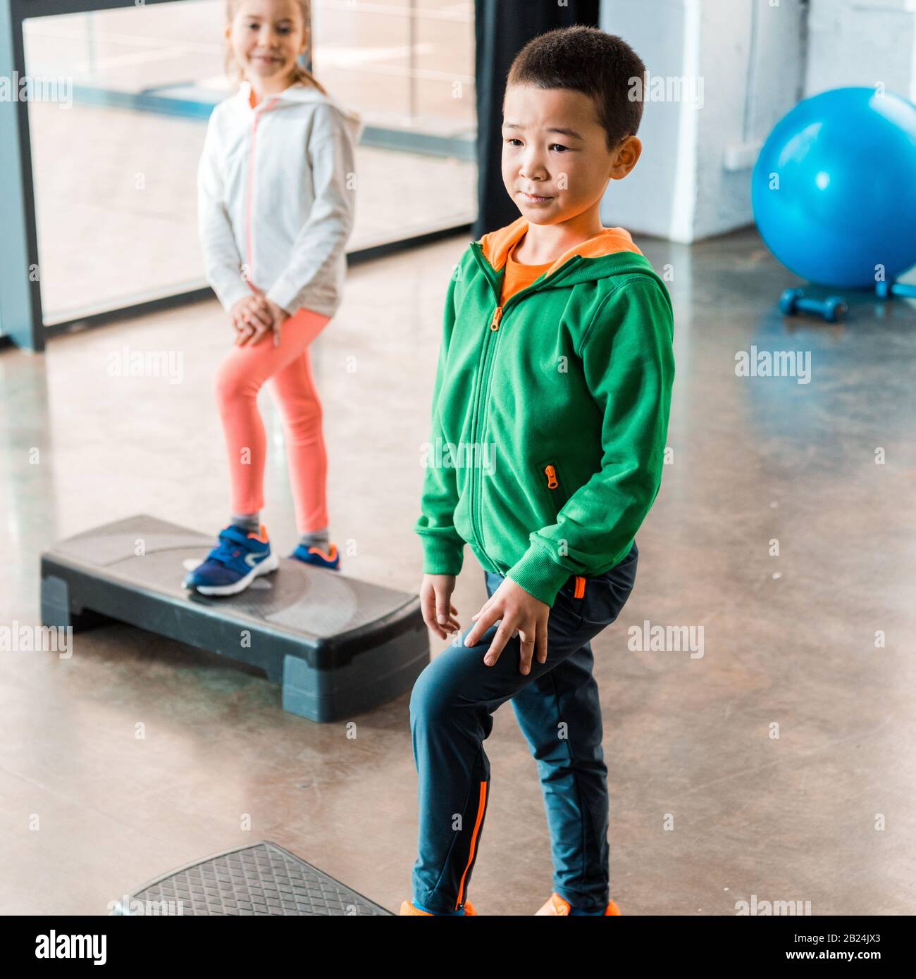 Selective focus of multicultural children doing exercise on step ...