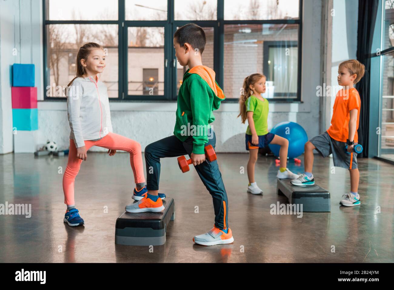 Selective focus of multiethnic children holding dumbbells and working ...