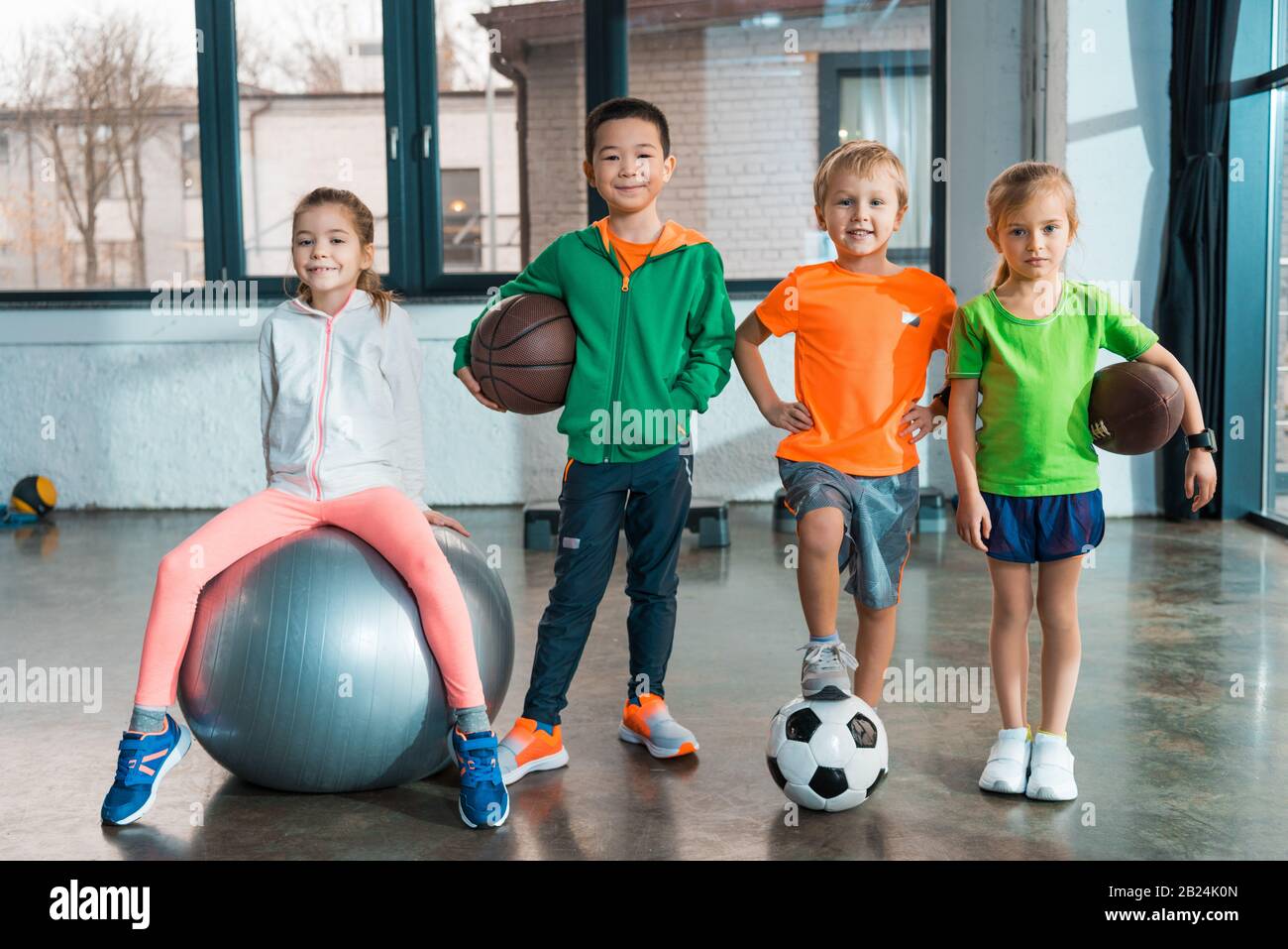 Front view of Child sitting on fitness ball next to multiethnic ...