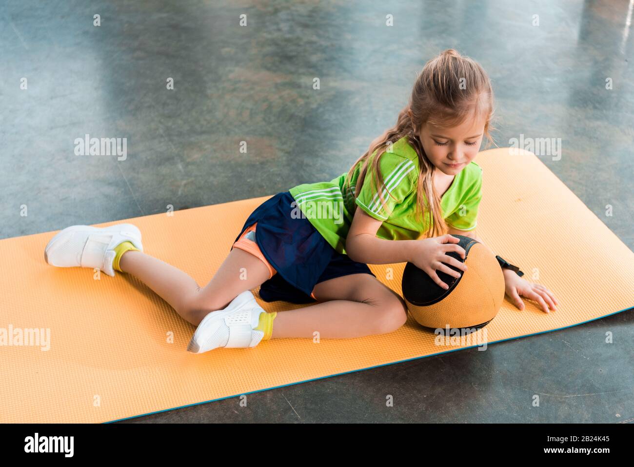 Child touching ball and lying on fitness mat in gym Stock Photo - Alamy
