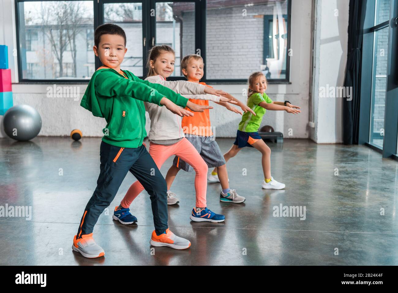 Side view of multiethnic children with outstretched hands doing lunges ...
