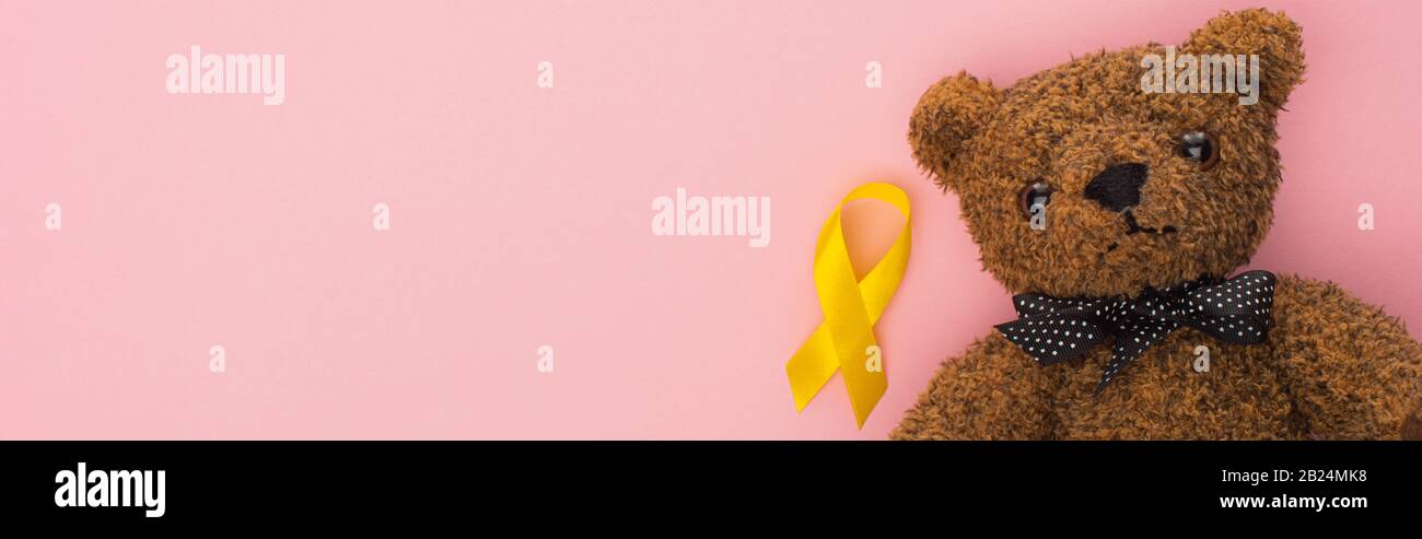 Top view of yellow ribbon and teddy bear on pink background, panoramic ...