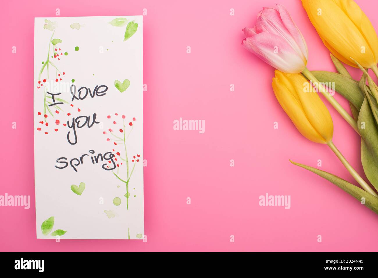 Top view of tulips and card with I love you spring lettering on pink ...