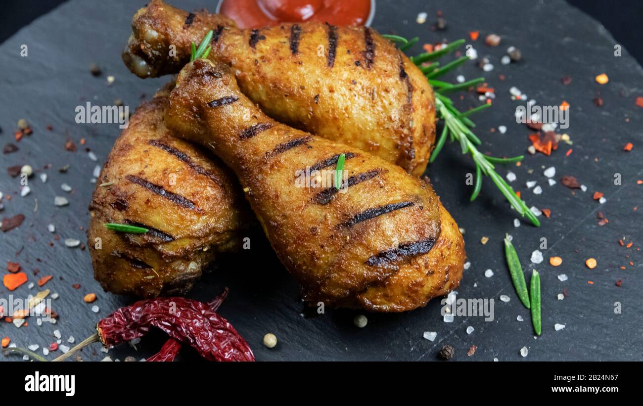 grilled chicken legs with red sauce on a black stone surface Stock ...