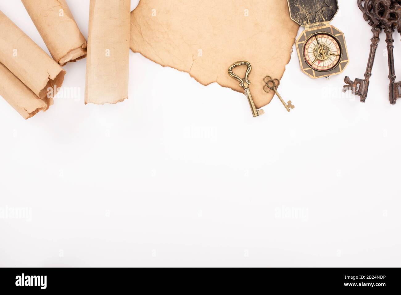 top view of vintage keys and compass on aged paper isolated on white ...
