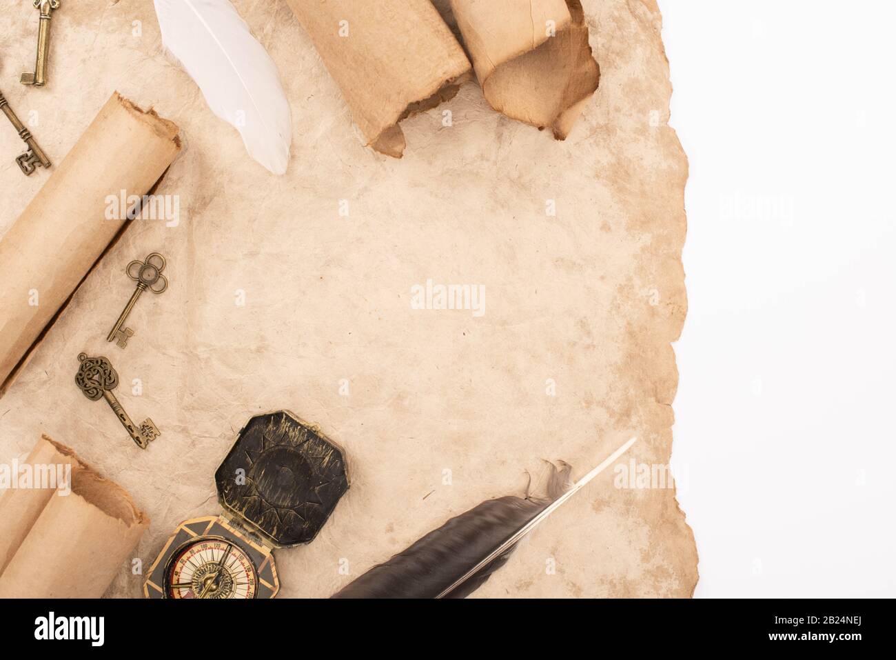 top view of feathers, vintage keys and compass on aged paper isolated ...