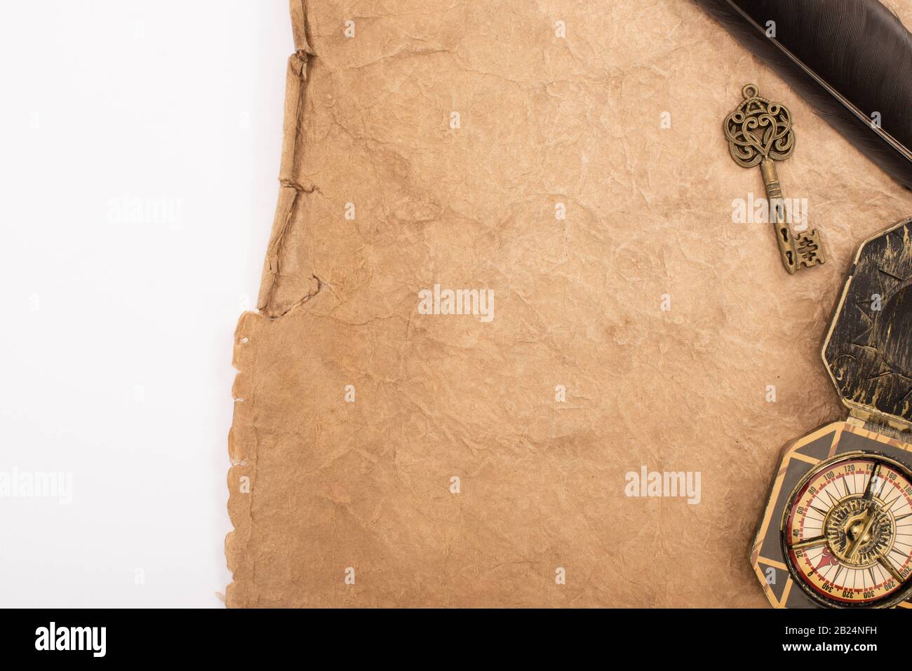 top view of feather, vintage key and compass on aged paper isolated on ...