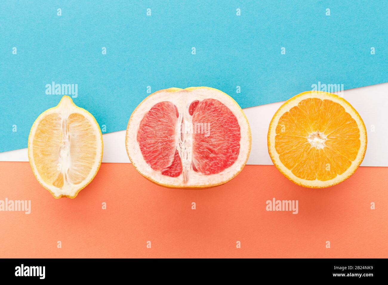 Top view of fruits halves on blue, orange and white background Stock ...