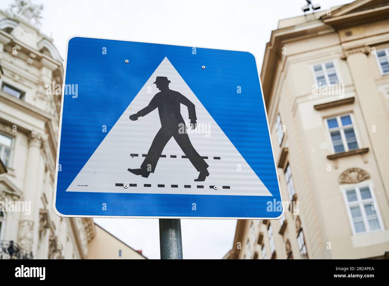 crosswalk sign, blue pedestrian symbol in front of buildings in Vienna ...
