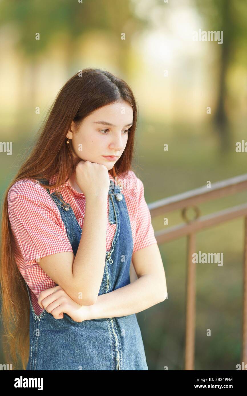 Brooding long-haired beautiful teenage girl is thinking about something ...
