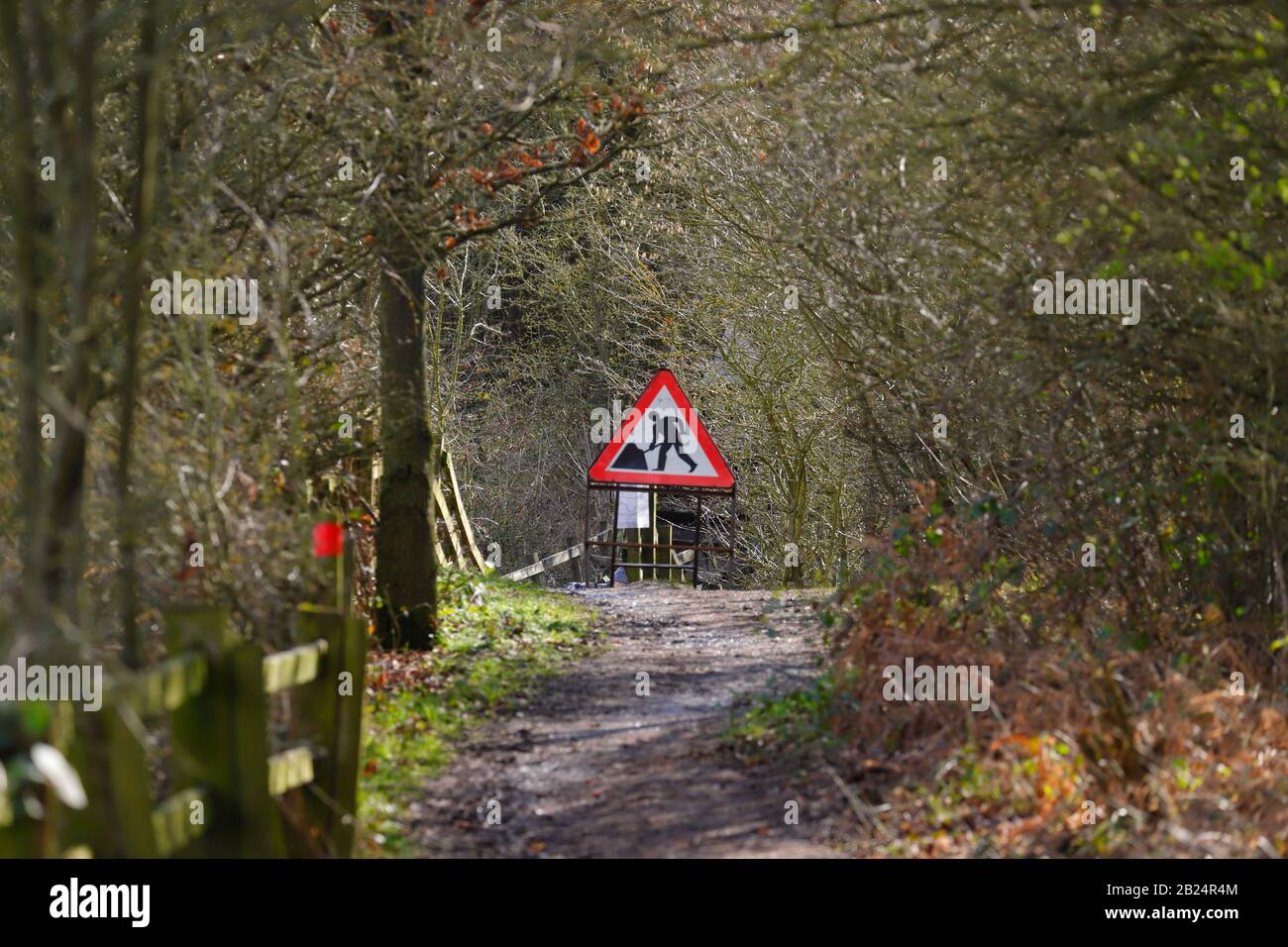 A road works sign is placed on a country footpath, to warn pedestrians ...
