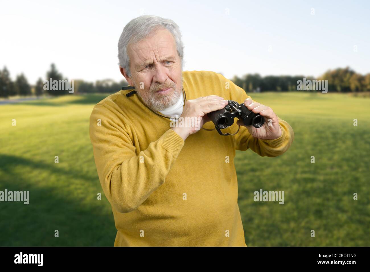 Old man with binoculars puzzled looking at sometning Stock Photo - Alamy