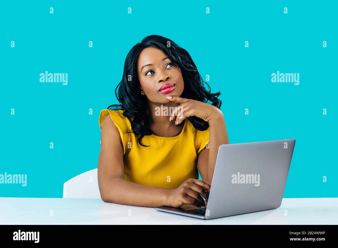 Portrait of a young woman sitting behind desk and computer laptop ...