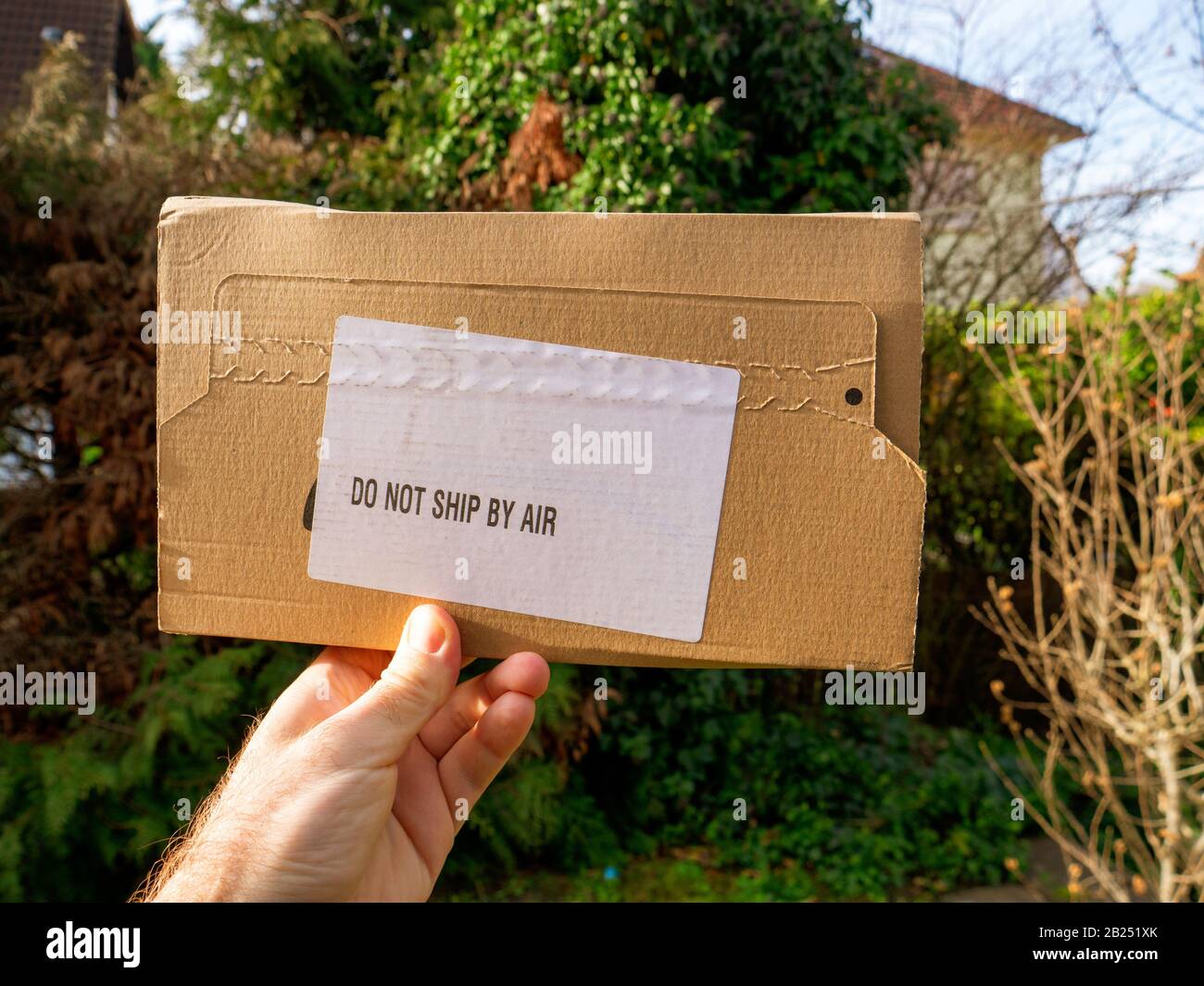 Man hand holding cardboard parcel envelope against green background ...