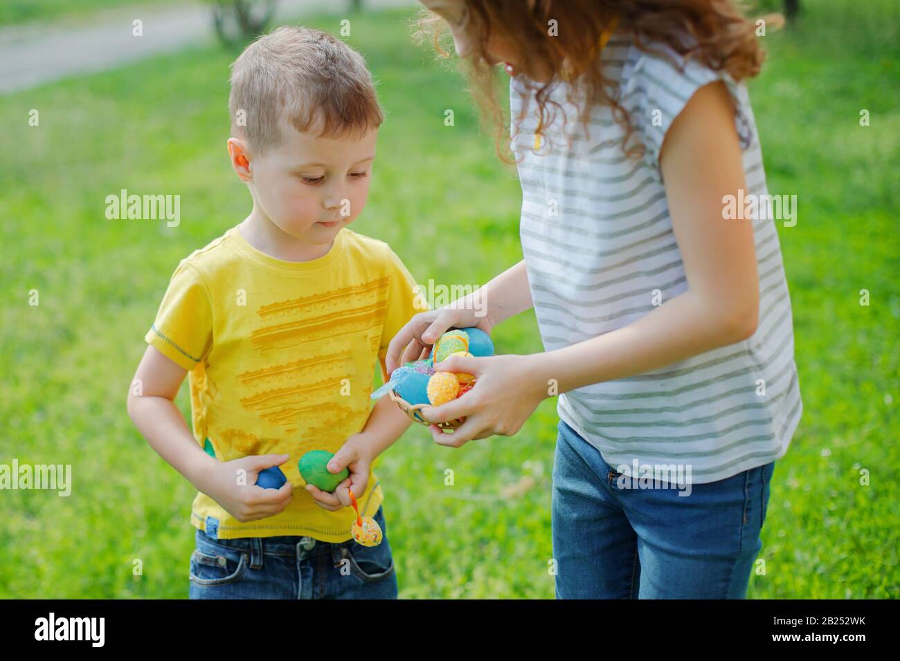 little boy shares Easter eggs with his sister. girl and a boy hold eggs ...