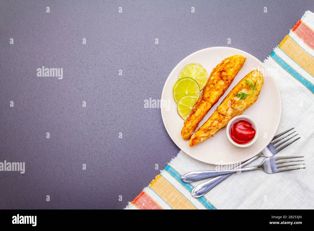 Grilled (fried) pollock in batter. On ceramic plate with lime, parsley ...