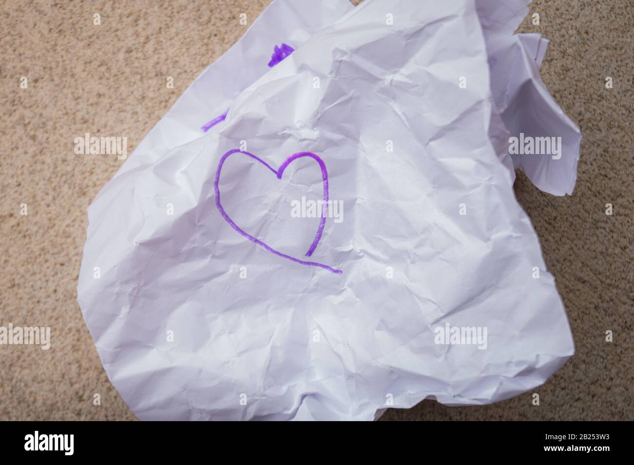 Crumpled paper on the ground with a heart shape drawing Stock Photo - Alamy