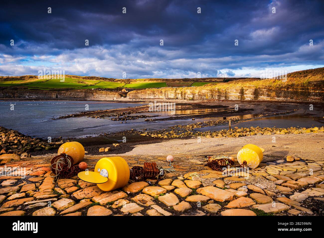 The low sun casts a golden glow onto the Jurassic cliffs and rocks of ...
