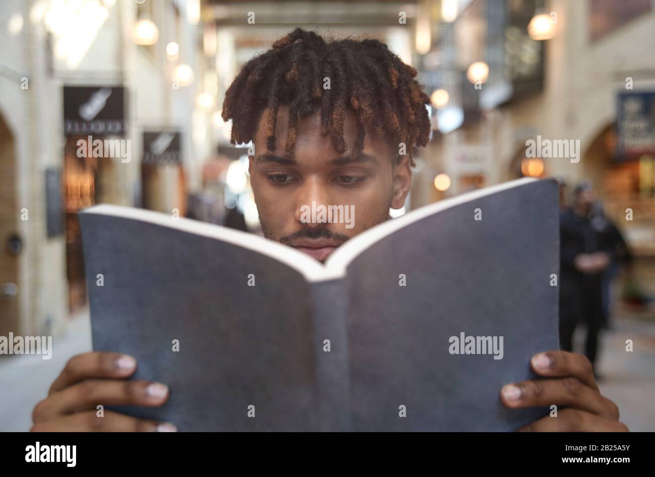 Millenial Reading a Book under a Modern Unfocused Background. Learning ...