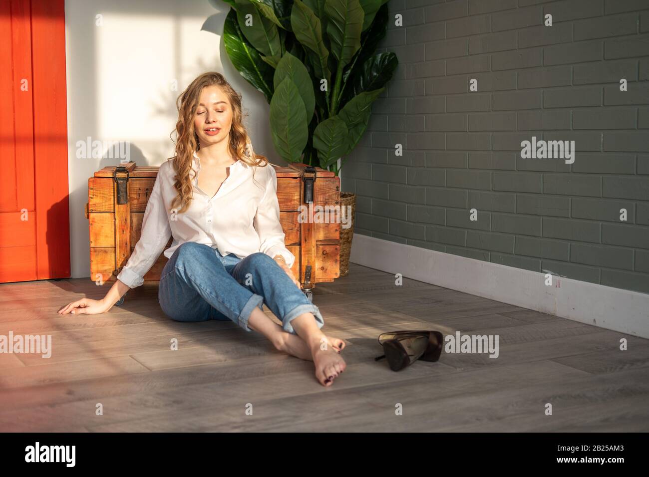 Young beautiful woman sitting on the floor with bare feet next to ...