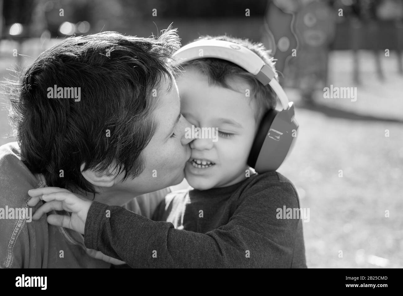 mother and son, mother kissing the boy, boy wears headphones, portrait ...