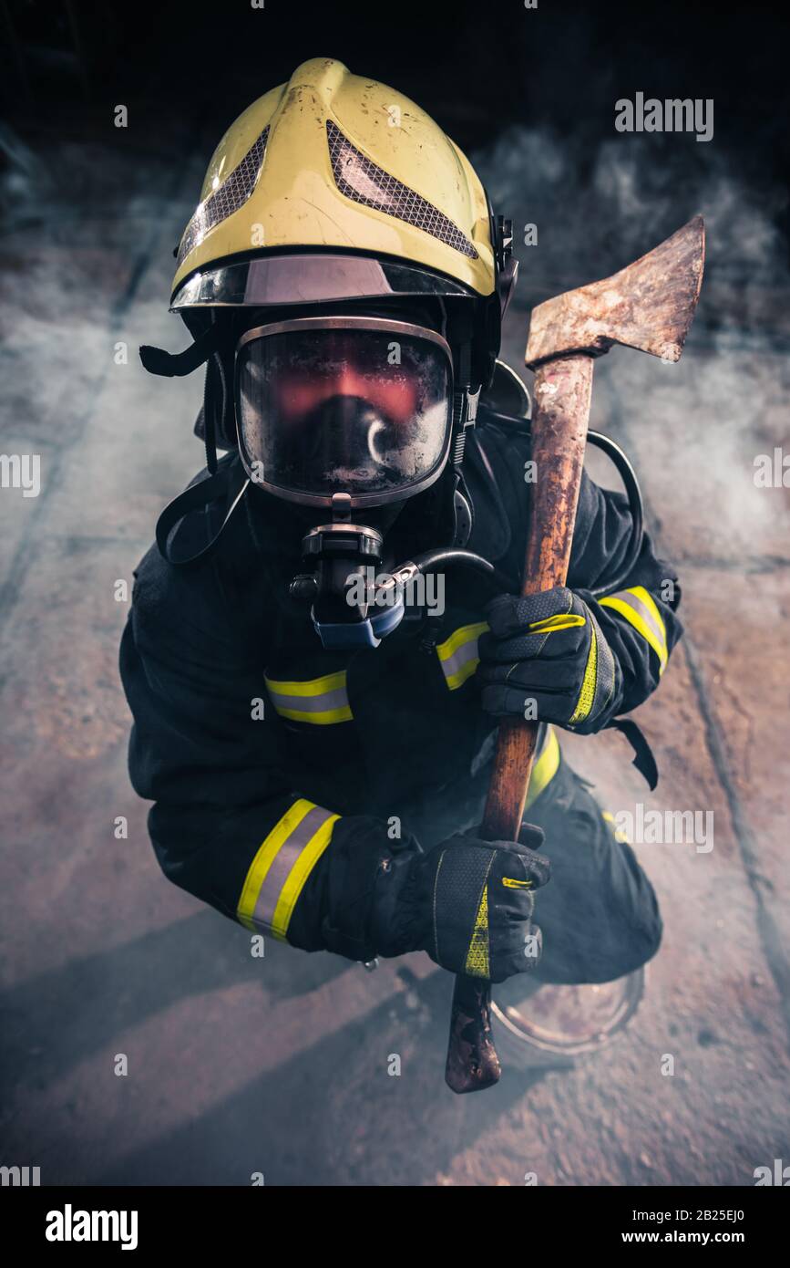 Portrait of a female firefighter while holding an axe and wearing an ...