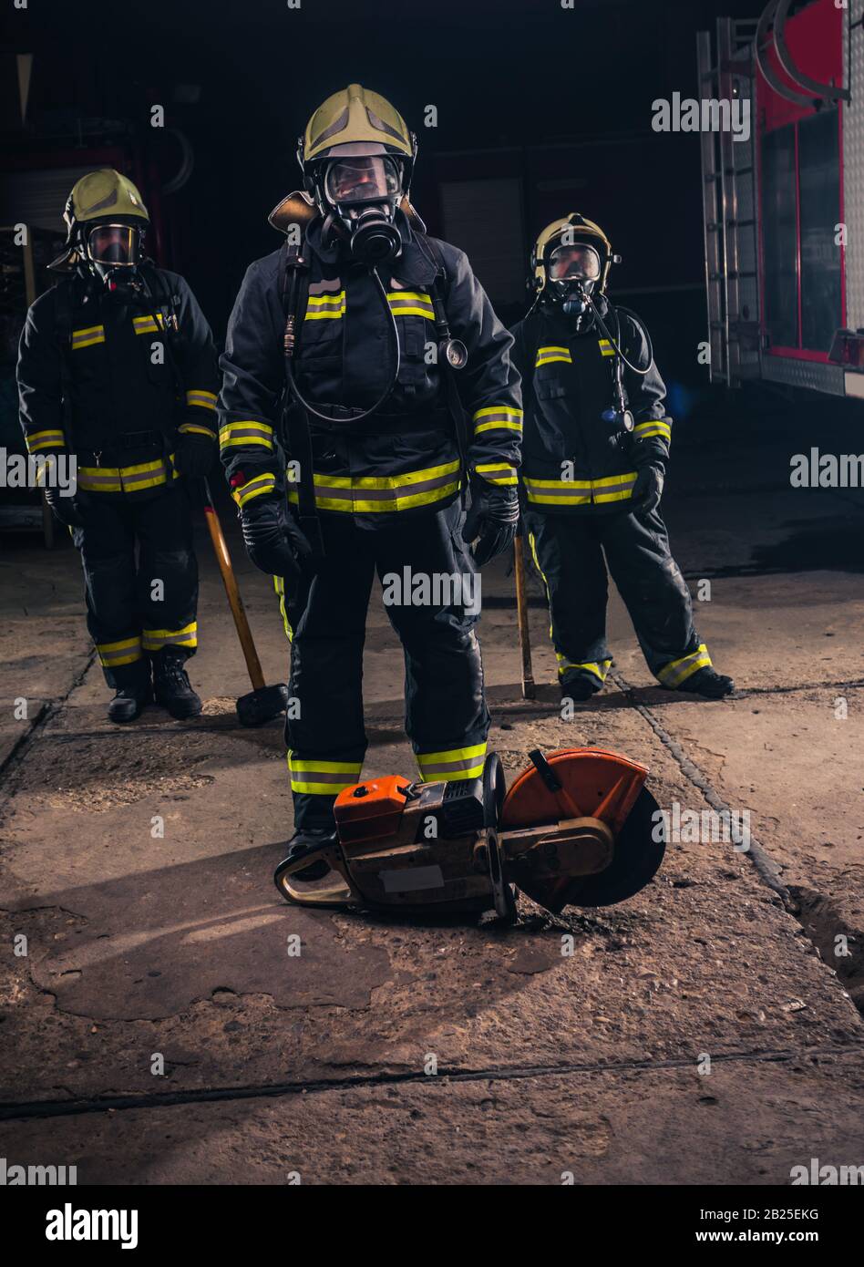 Group of three young fireman posing inside the fire department with ...
