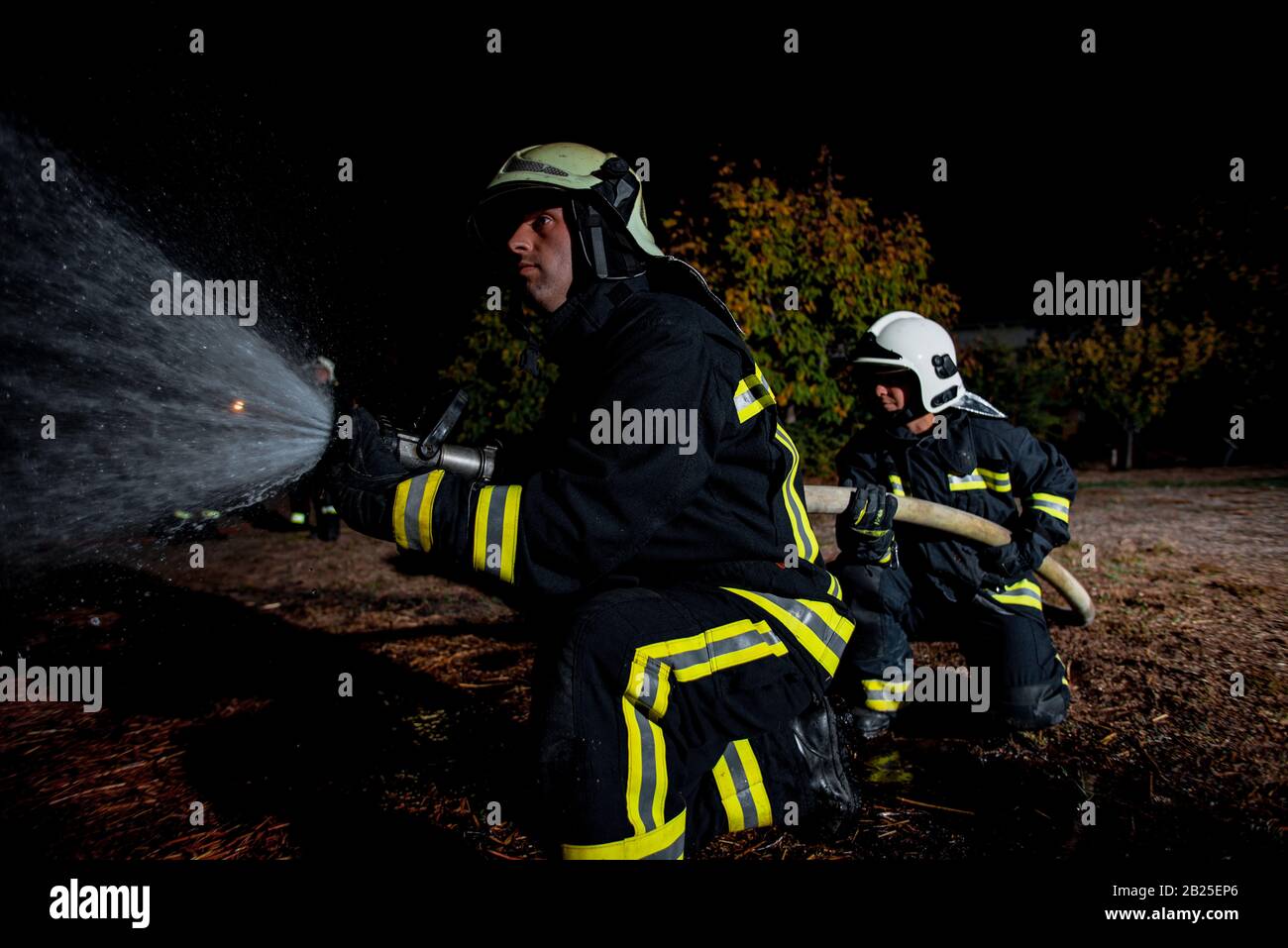 Fireman team in full equipment with helmets and gas masks fighting a ...