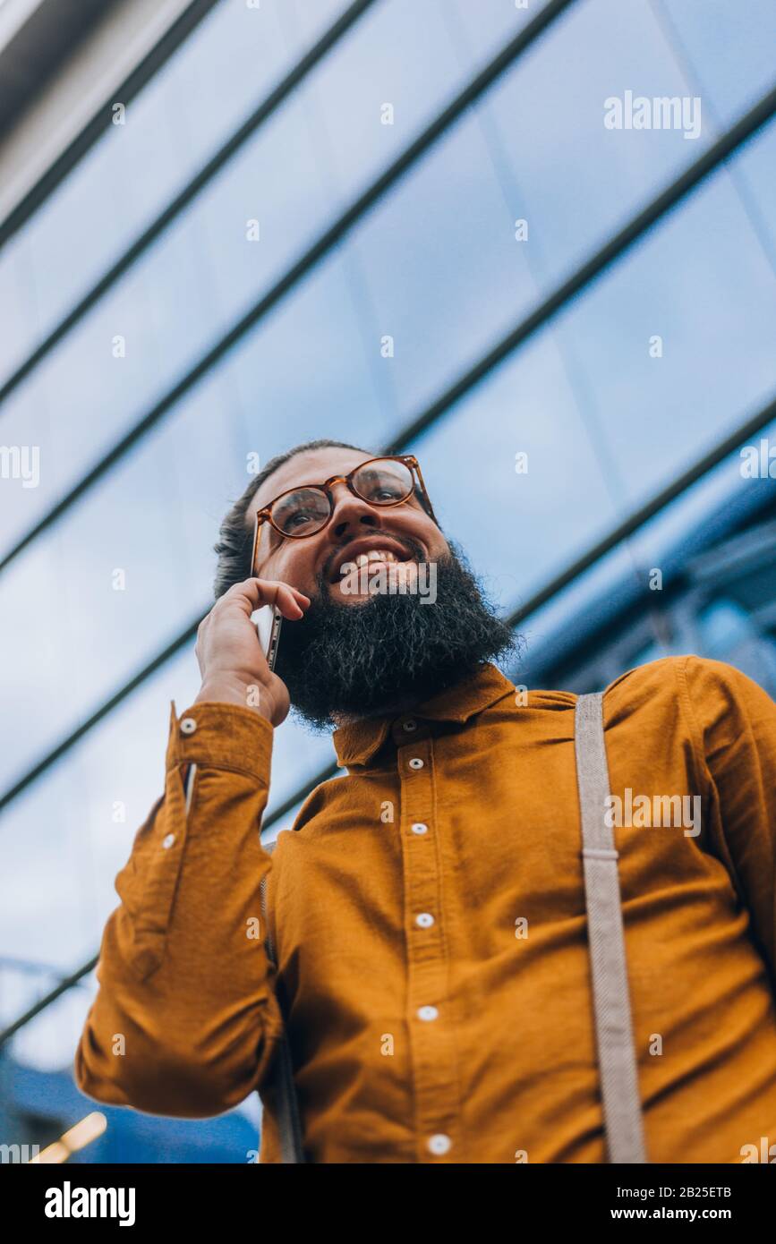 Modern hipster guy with long hair and beard at the city promenade ...
