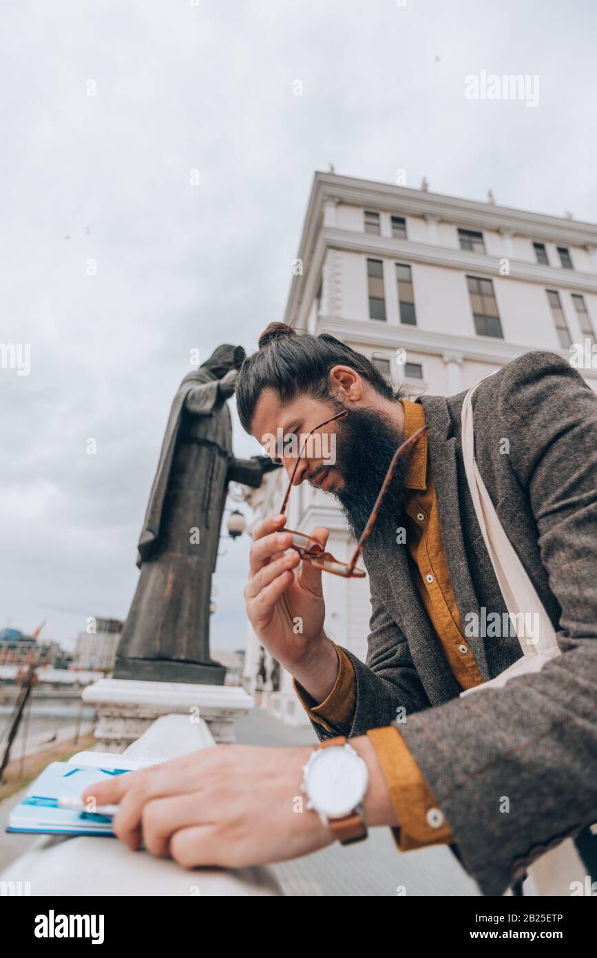 Modern day hipster reading a book at the city river during daytime ...