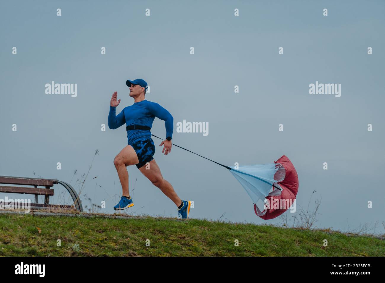 Muscular man wearing sport clothes during a running parachute exercise ...