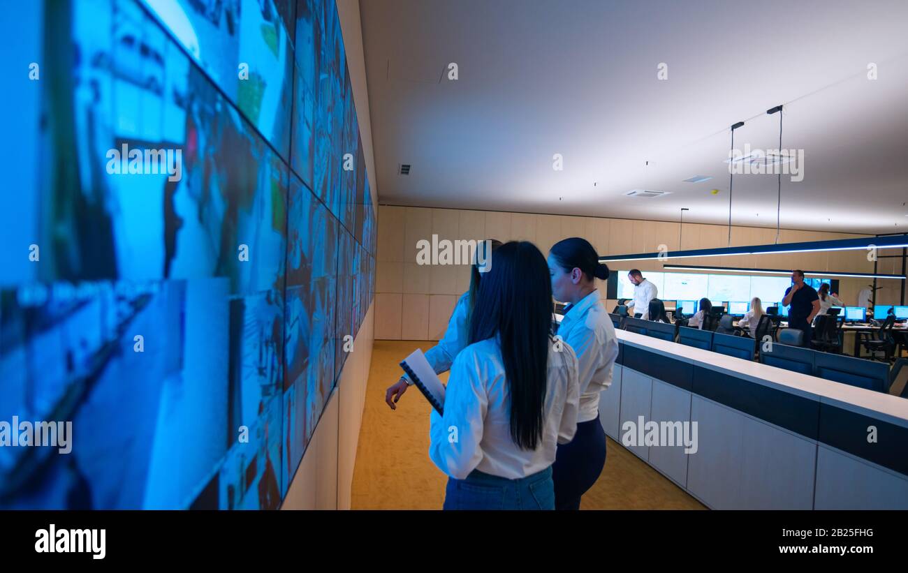 Security guards standing in front of a large CCTV monitor at the main ...