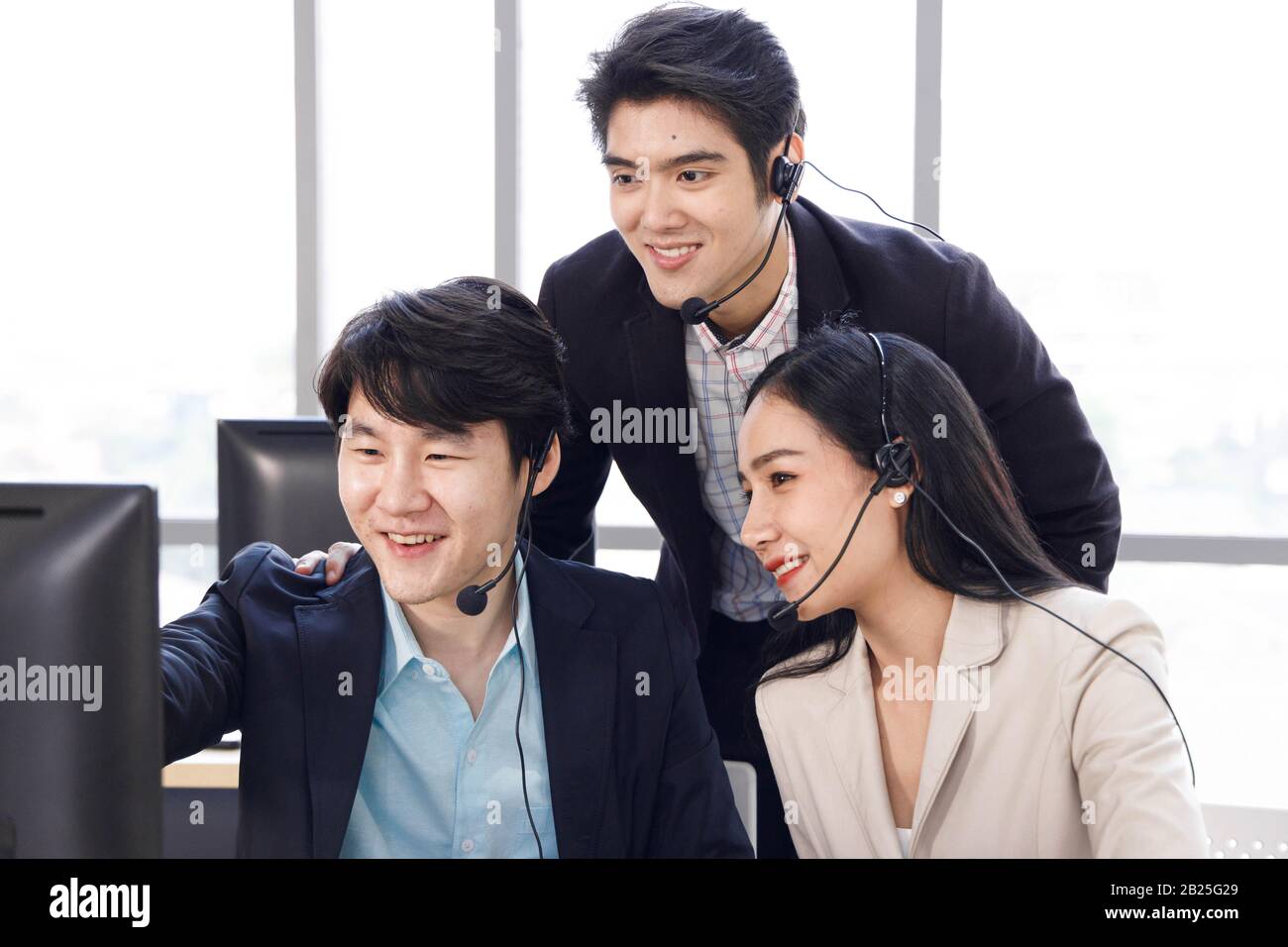 Three happy Asian call center operator agent working together and help ...