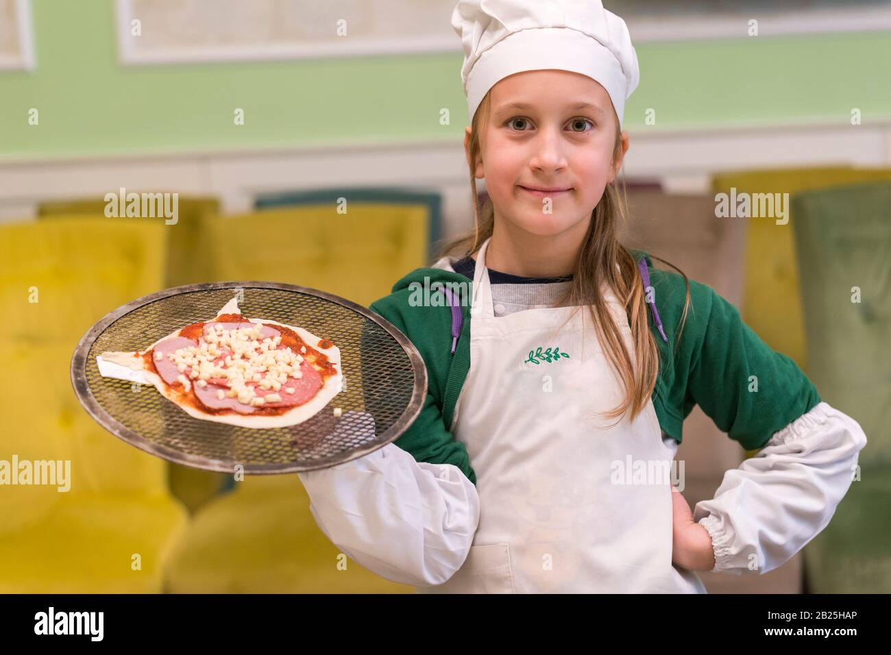 Little girl preparing homemade pizza. Beautiful little girl in a chef ...